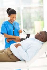 young african doctor checking senior patient's blood pressure - Jay Harold