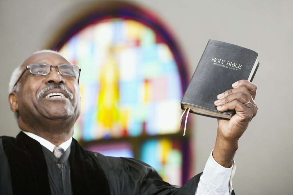 African American Reverend holding up Bible - Jay Harold